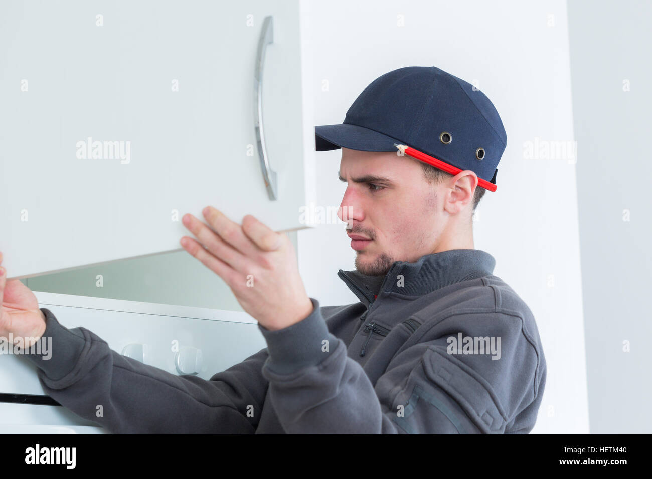handyman fixing the cupboard in the kitchen Stock Photo - Alamy