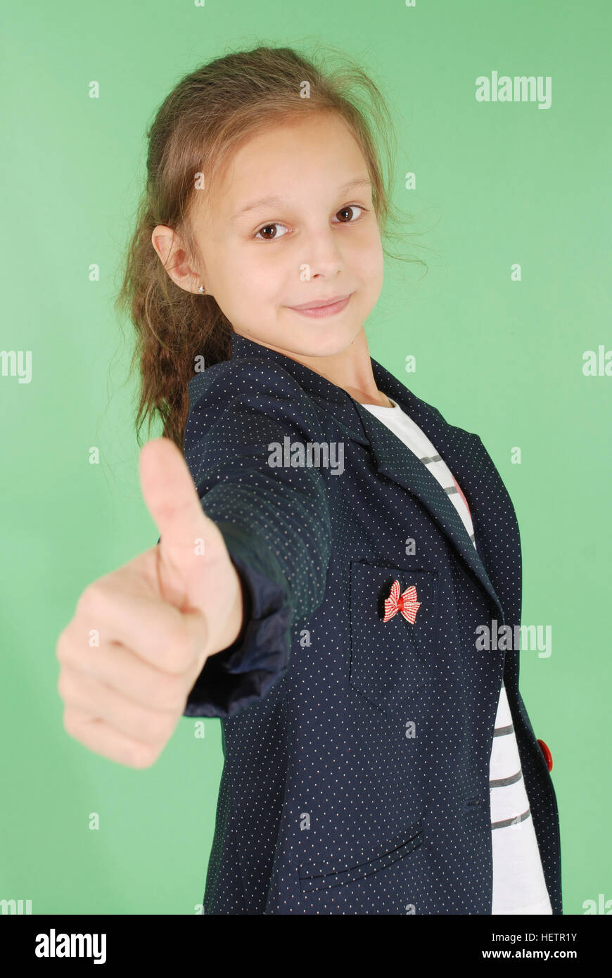 Smiling young school girl showing thumbs up isolated on green ...