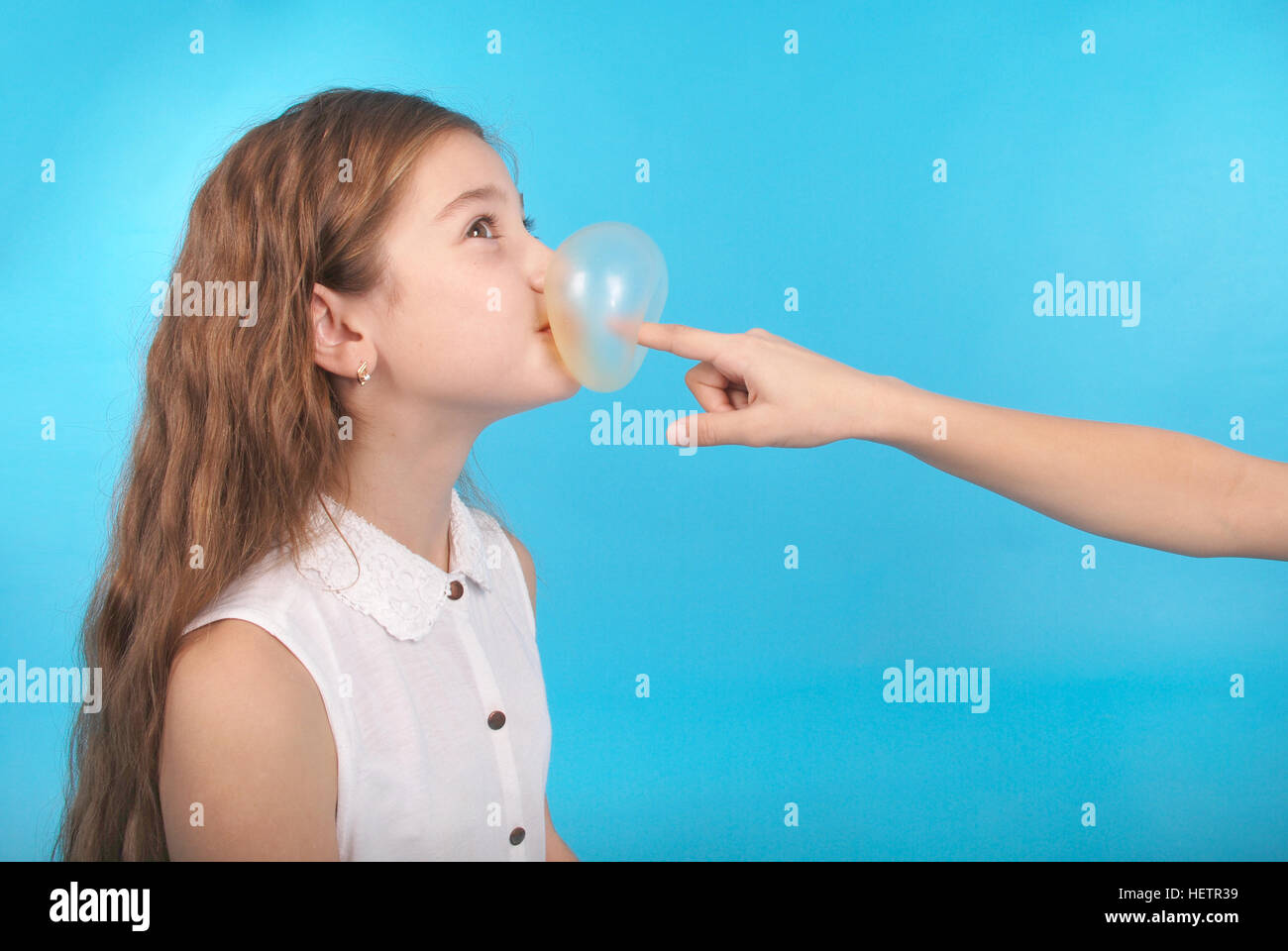 Two young girls playing with chewing gum isolated on blue Stock Photo ...