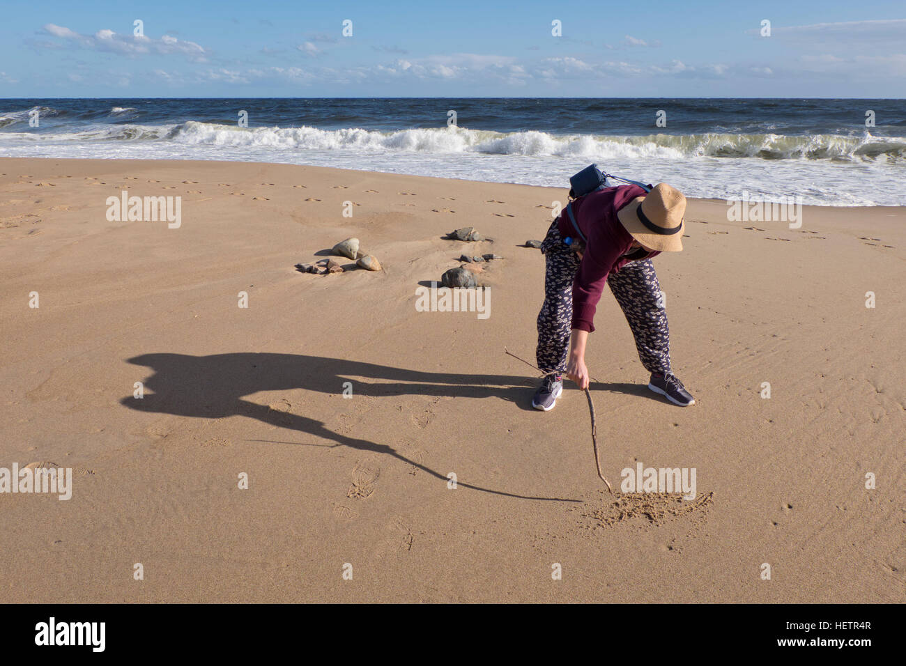 Young woman drawing on the sand on the beach in Punta Colorada, Uruguay ...