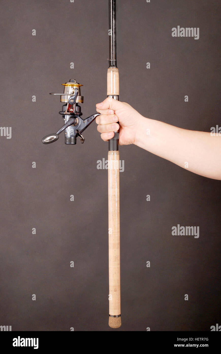 Man's hand holding a fishing rod on a black background Stock Photo - Alamy