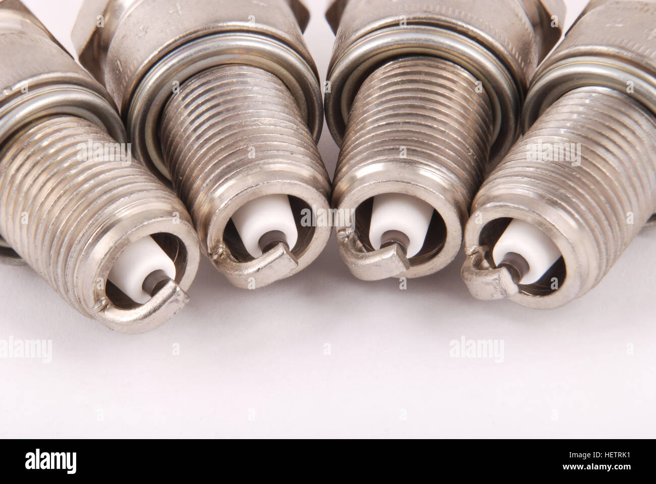 Four new spark plugs on a gray background Stock Photo - Alamy
