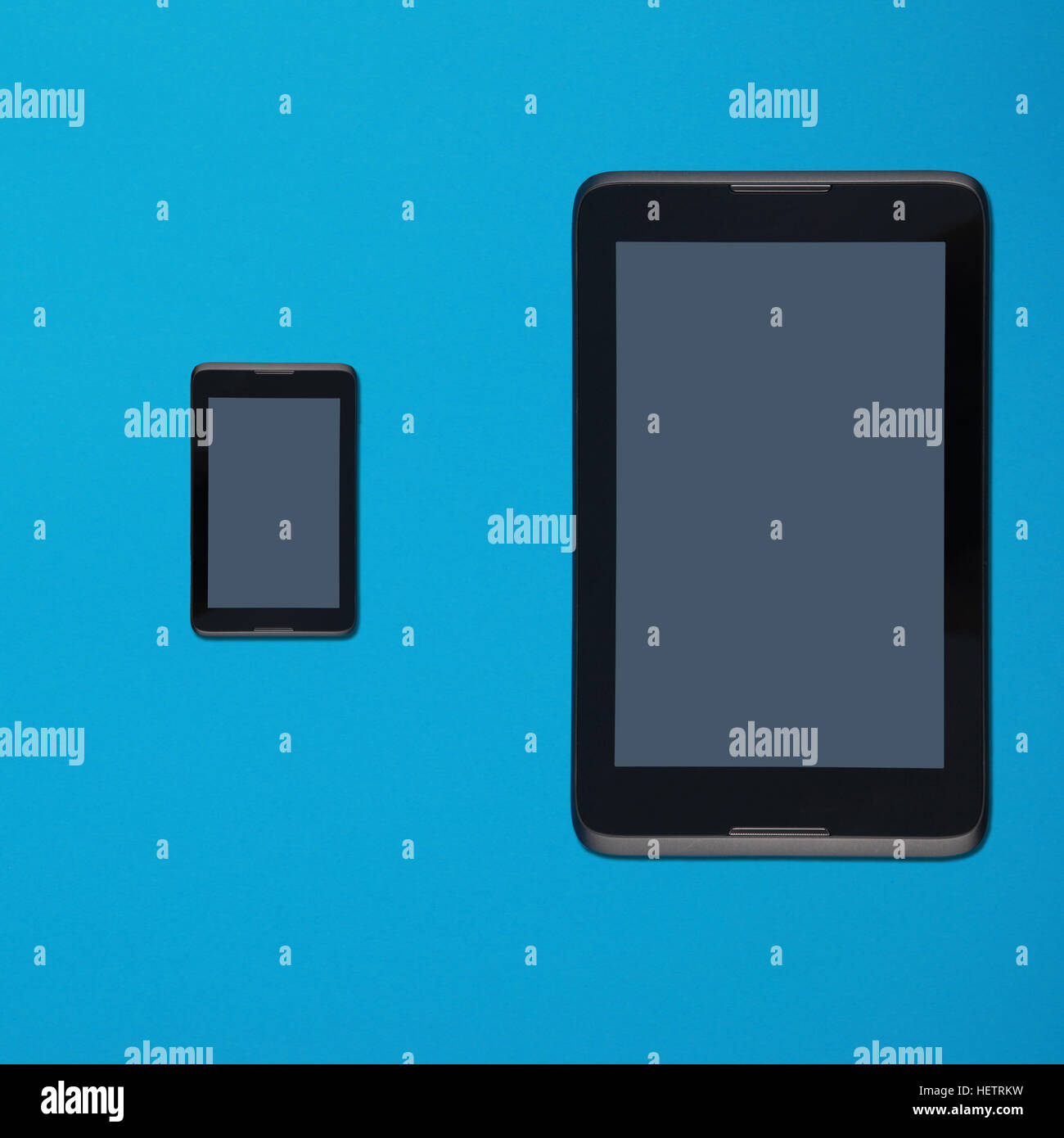 Tablet pc and smartphone lying side by side isolated on blue background ...