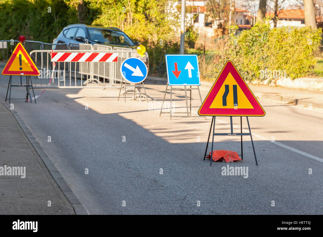 Road sign lane narrowing. In the background, blurred a roadworks site ...