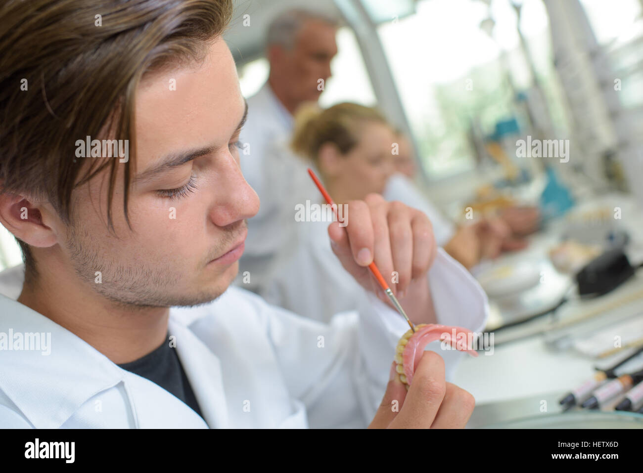 Male technician adding colour to dentures Stock Photo - Alamy
