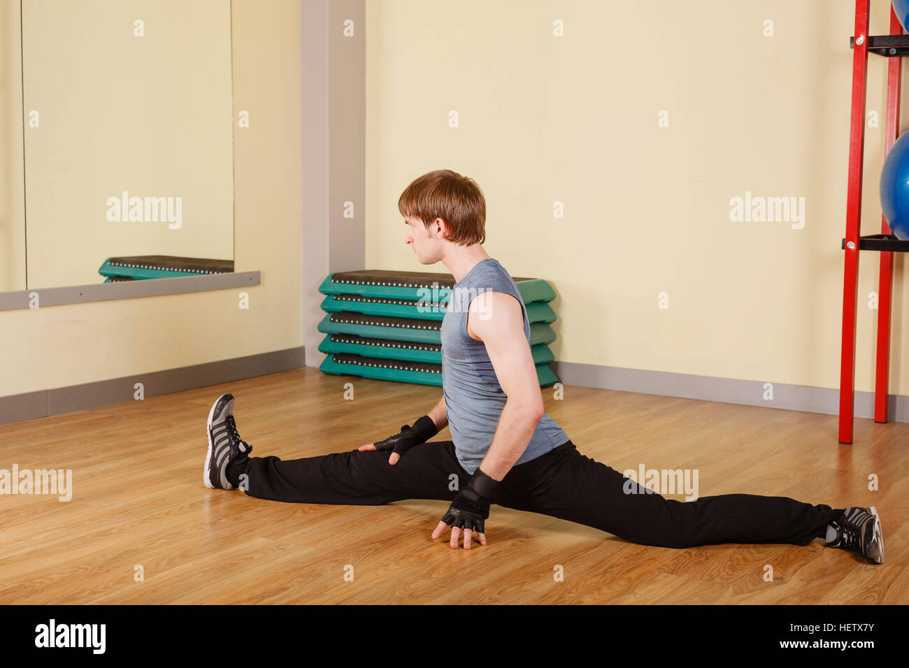 Man sits on a forward split. Stretching after exercise. Healthy ...