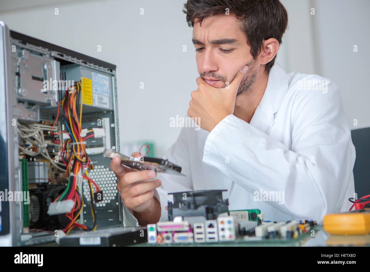 Confused computer technician studying component Stock Photo - Alamy