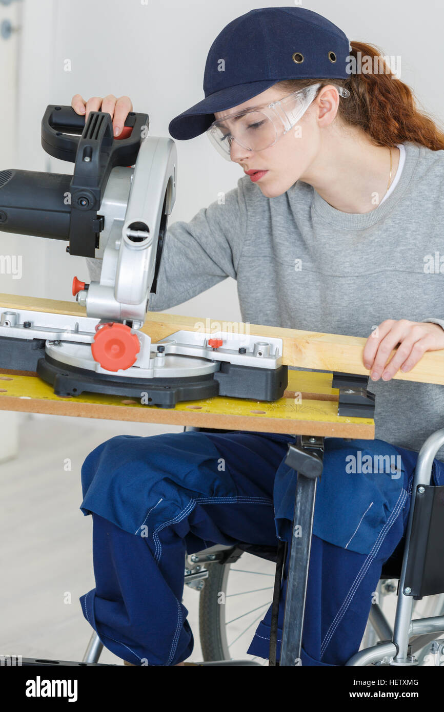 Young woman in wheelchair using circular saw Stock Photo - Alamy
