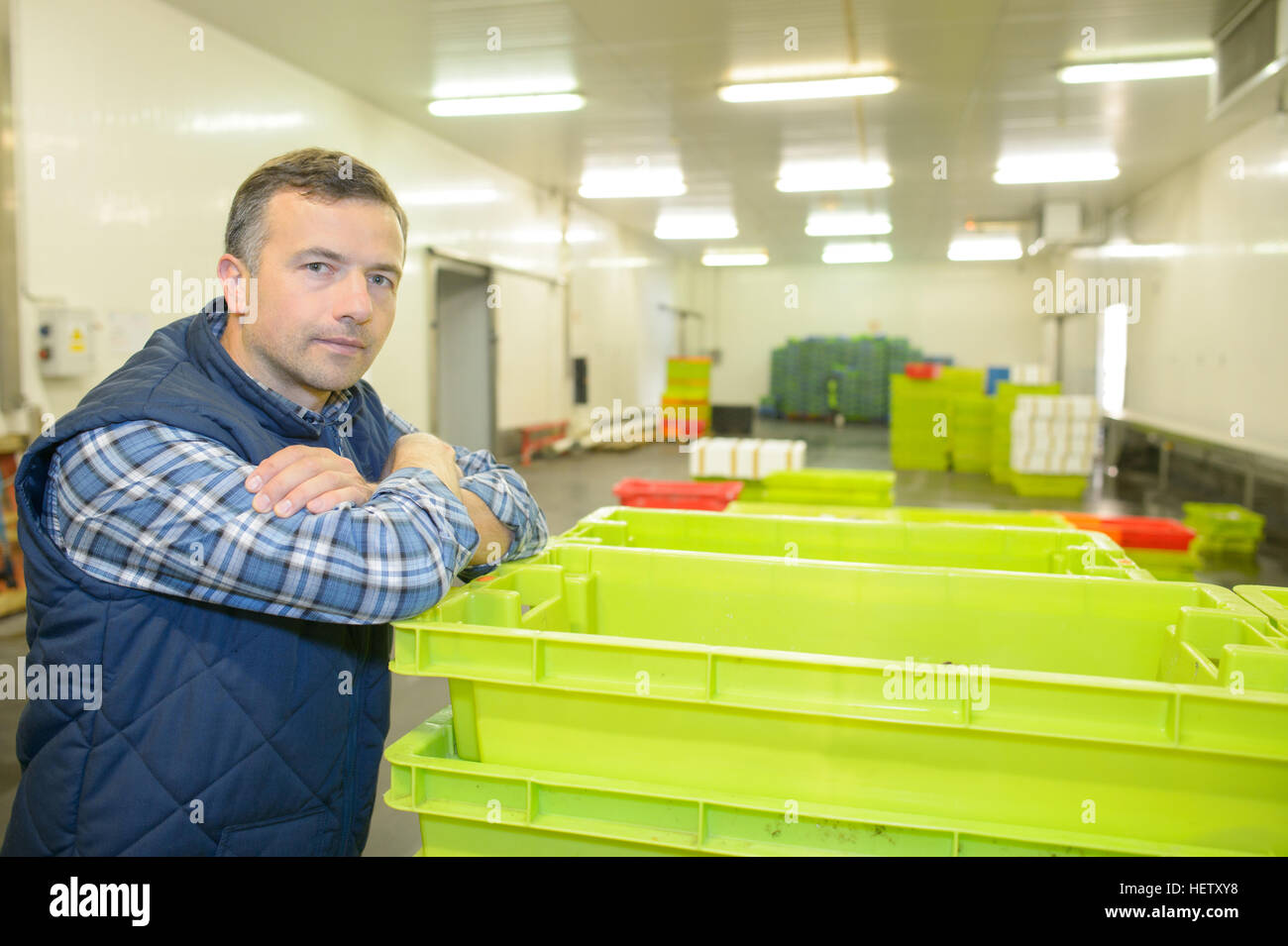 Portrait of worker leaning on plastic crate Stock Photo - Alamy