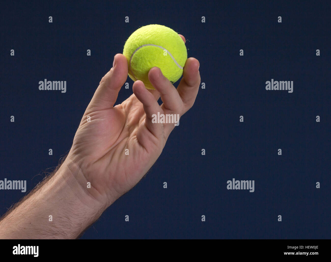 Hand hold Tennis ball on blue background Stock Photo - Alamy