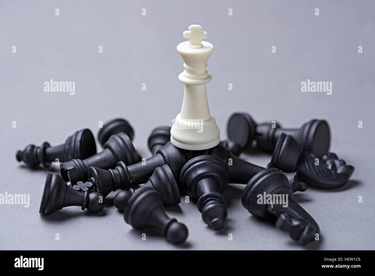 White king chess piece surrounded by fallen black pieces, success ...