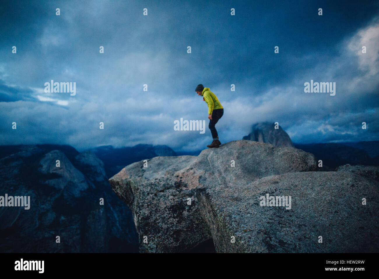 Mid adult man standing at top of mountain peering over edge, Yosemite ...