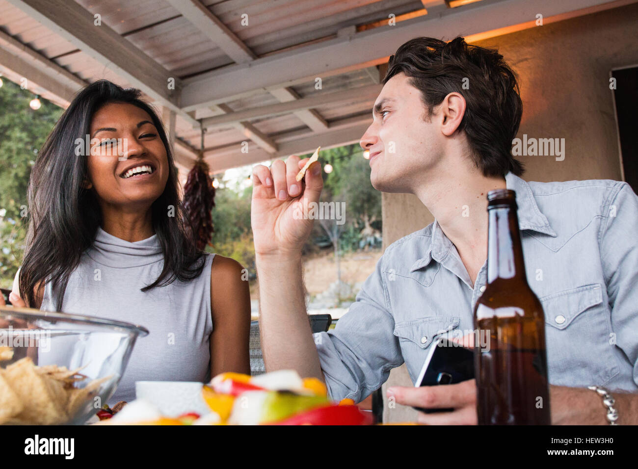 Young couple sitting on veranda, enjoying meal Stock Photo - Alamy