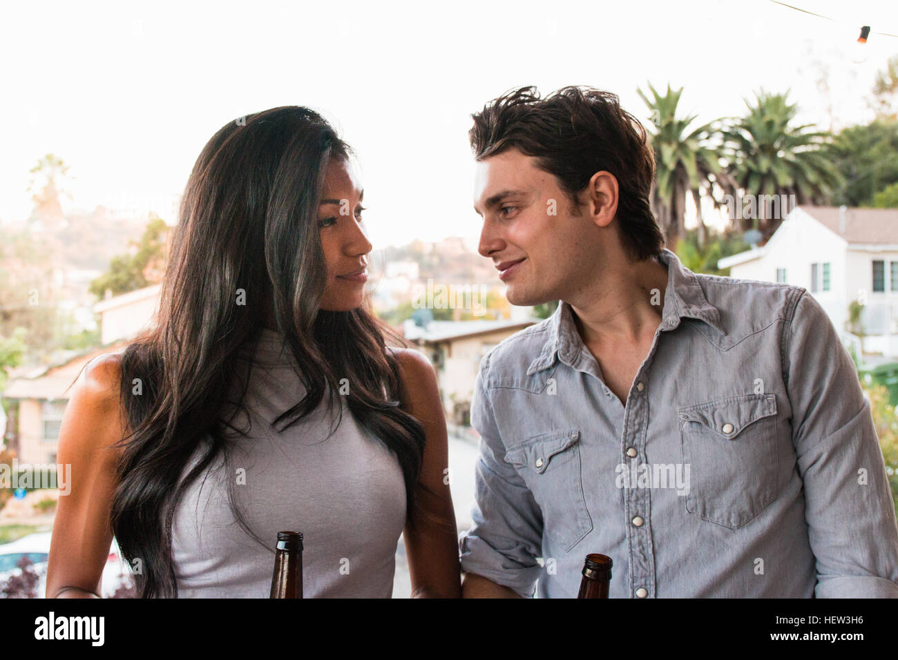 Young couple sitting on veranda, holding beer bottles Stock Photo - Alamy