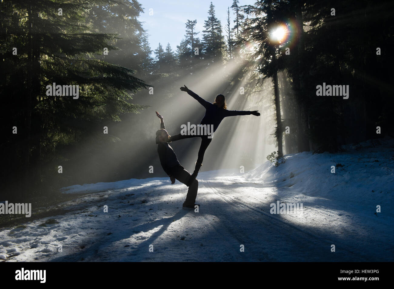 Silhouettes of acrobats in snow covered forest balancing, Frog lake ...