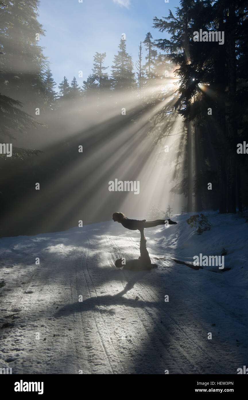 Silhouettes of acrobats in snow covered forest balancing, Frog lake ...
