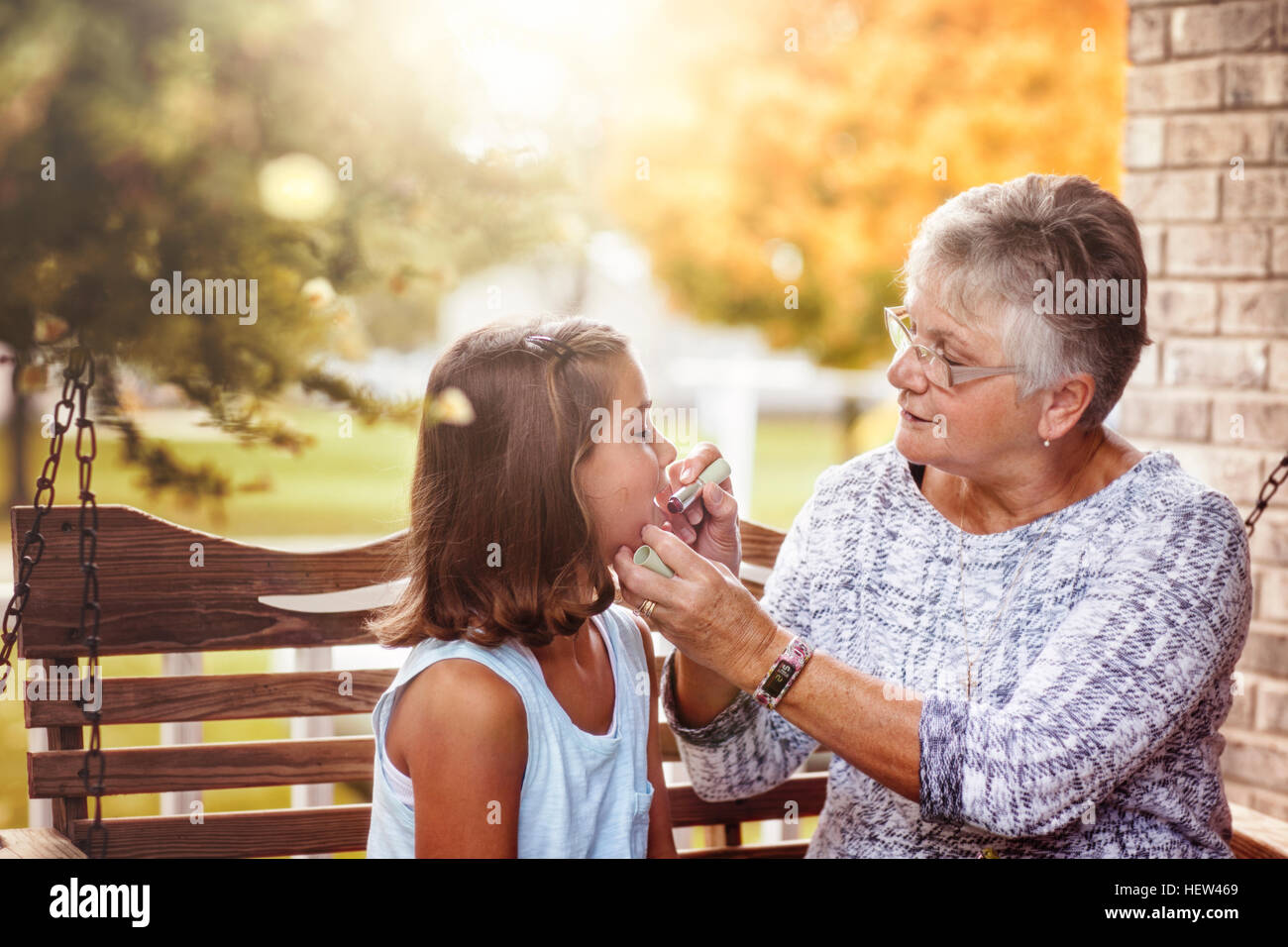 Grandmother And Granddaughter Sitting On Porch Swing Grandmother