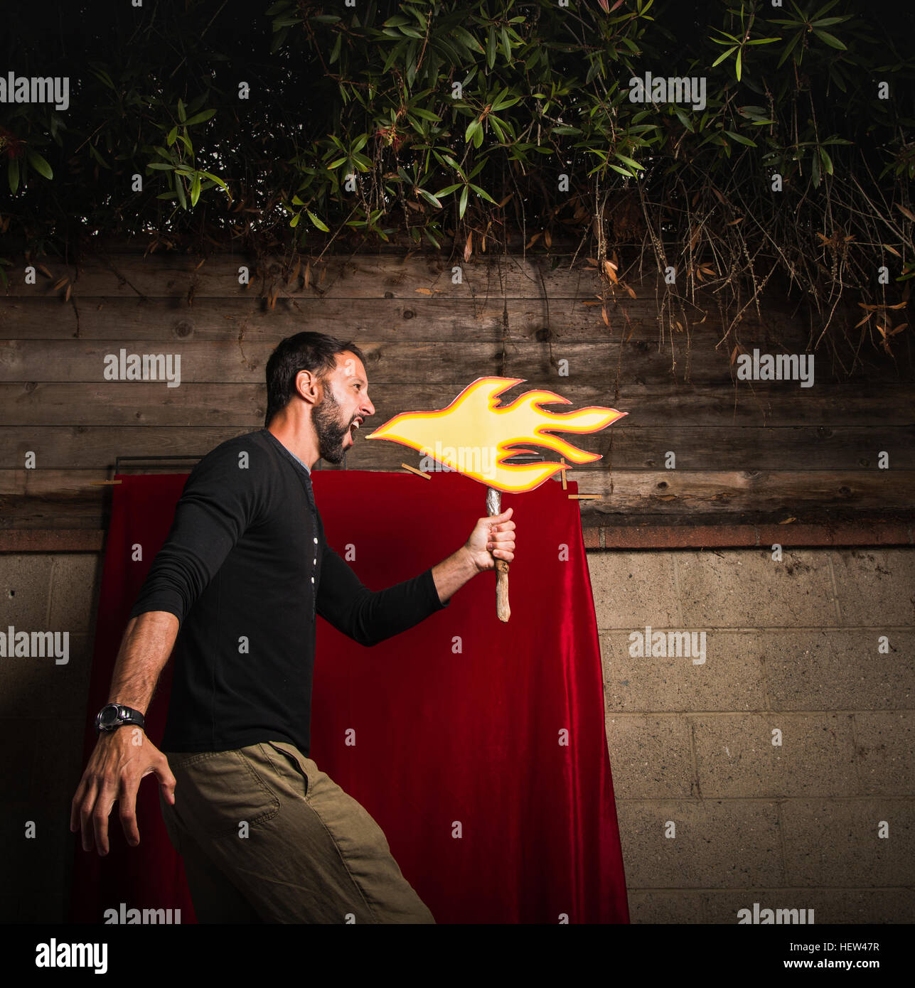 Man holding cardboard cut-out of flames pretending to breathe fire ...