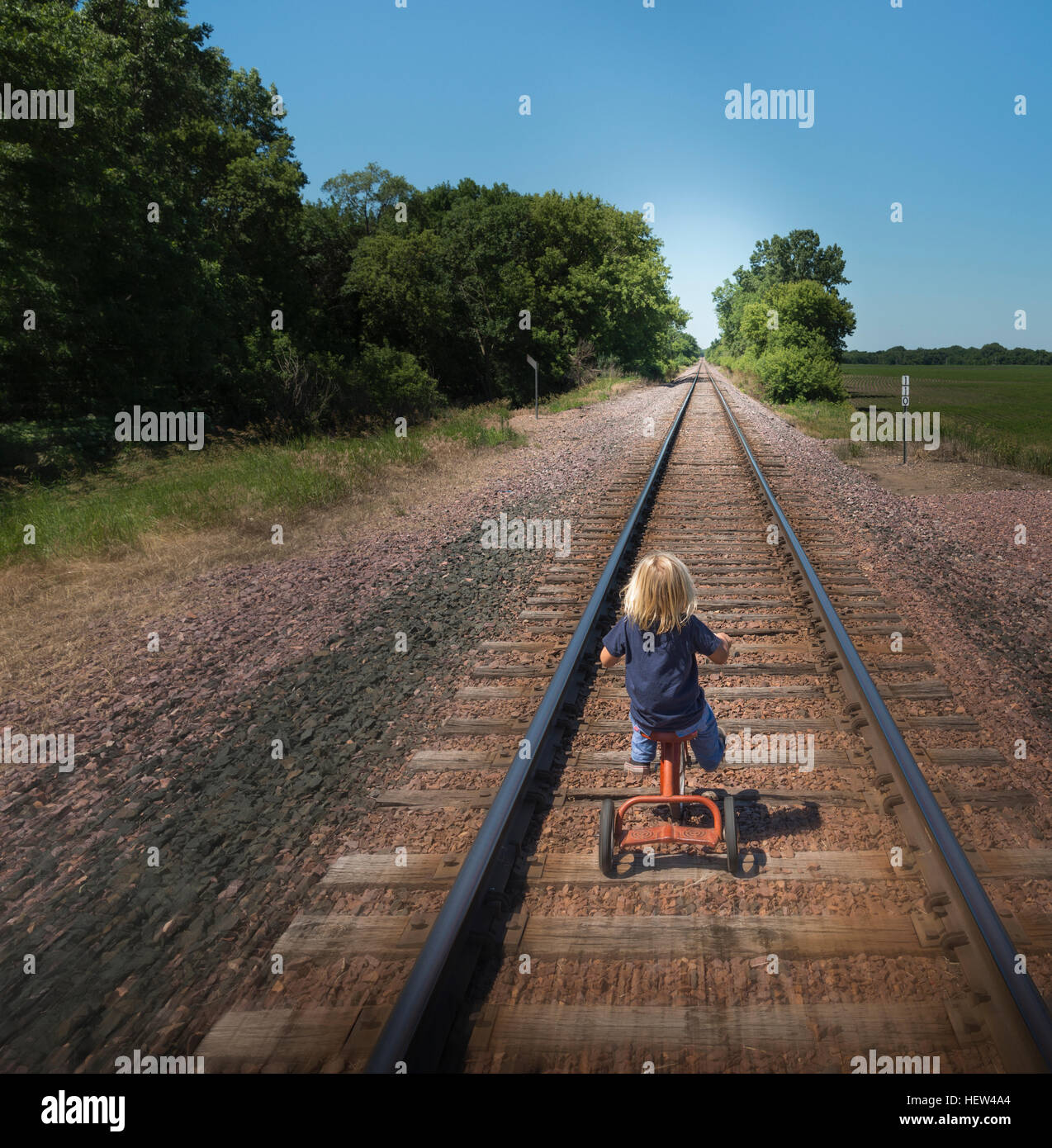 Rear view of boy riding tricycle on railway track Stock Photo - Alamy