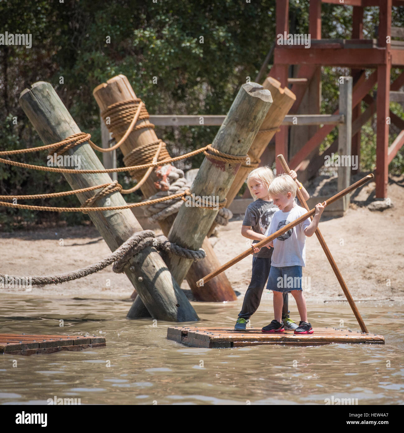 Boys holding sticks standing on raft Stock Photo - Alamy
