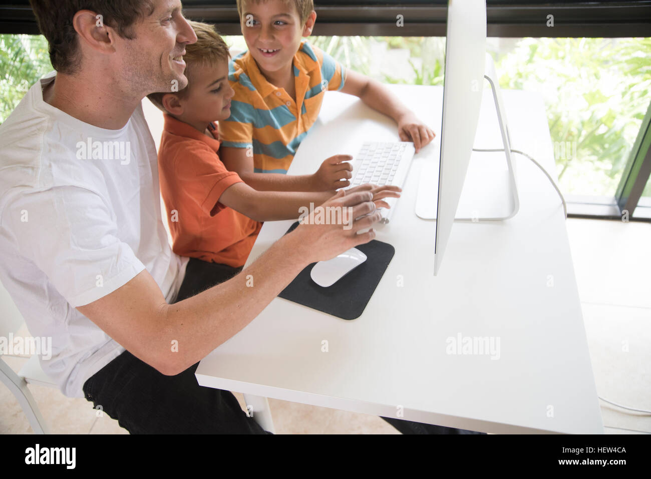 Man showing two sons how to use desktop computer Stock Photo - Alamy
