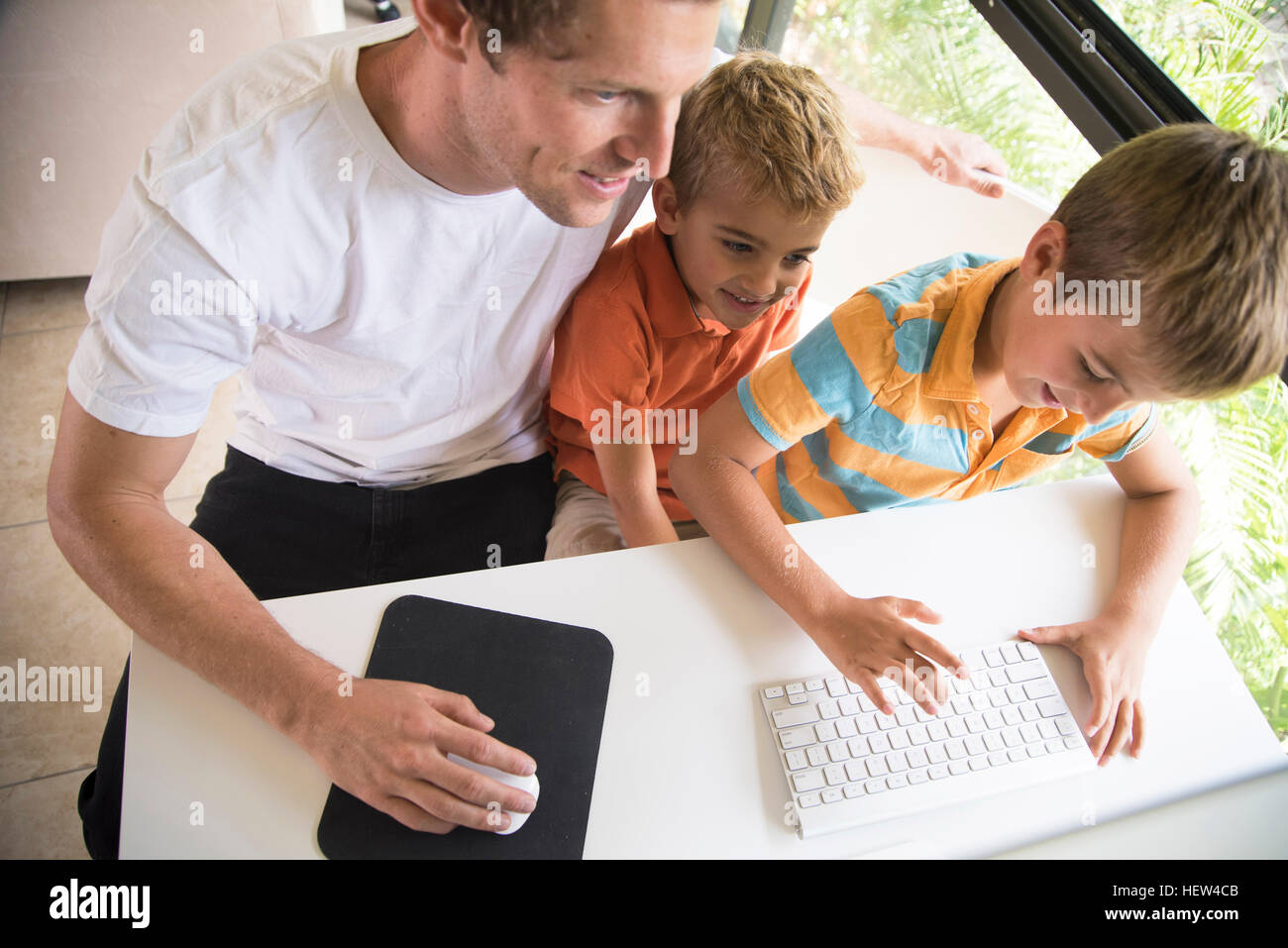 Man and two sons typing on desktop computer keyboard Stock Photo - Alamy