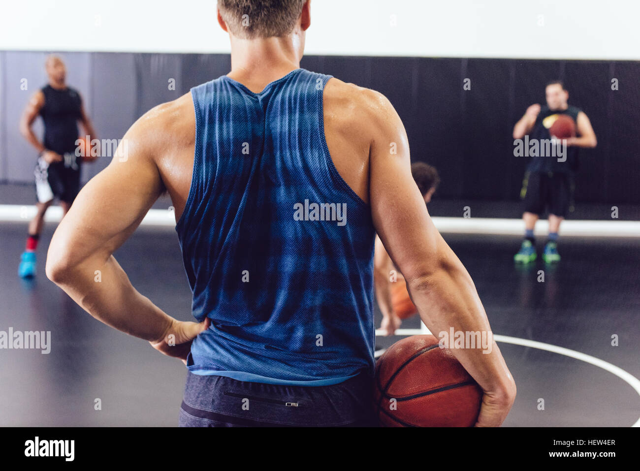 Rear view of male basketball player holding ball on court Stock Photo ...