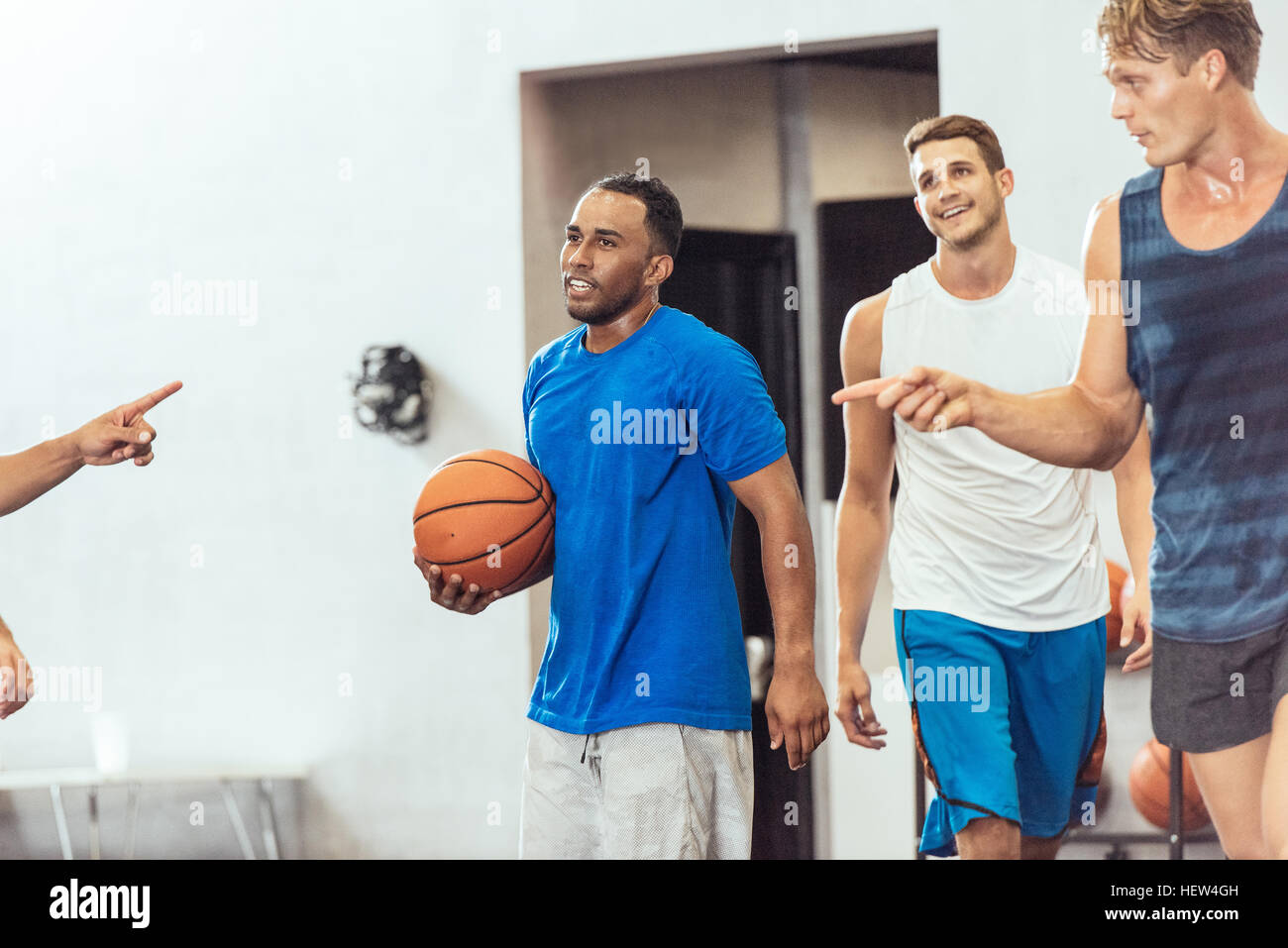 Two male basketball players pointing at each other on basketball court ...