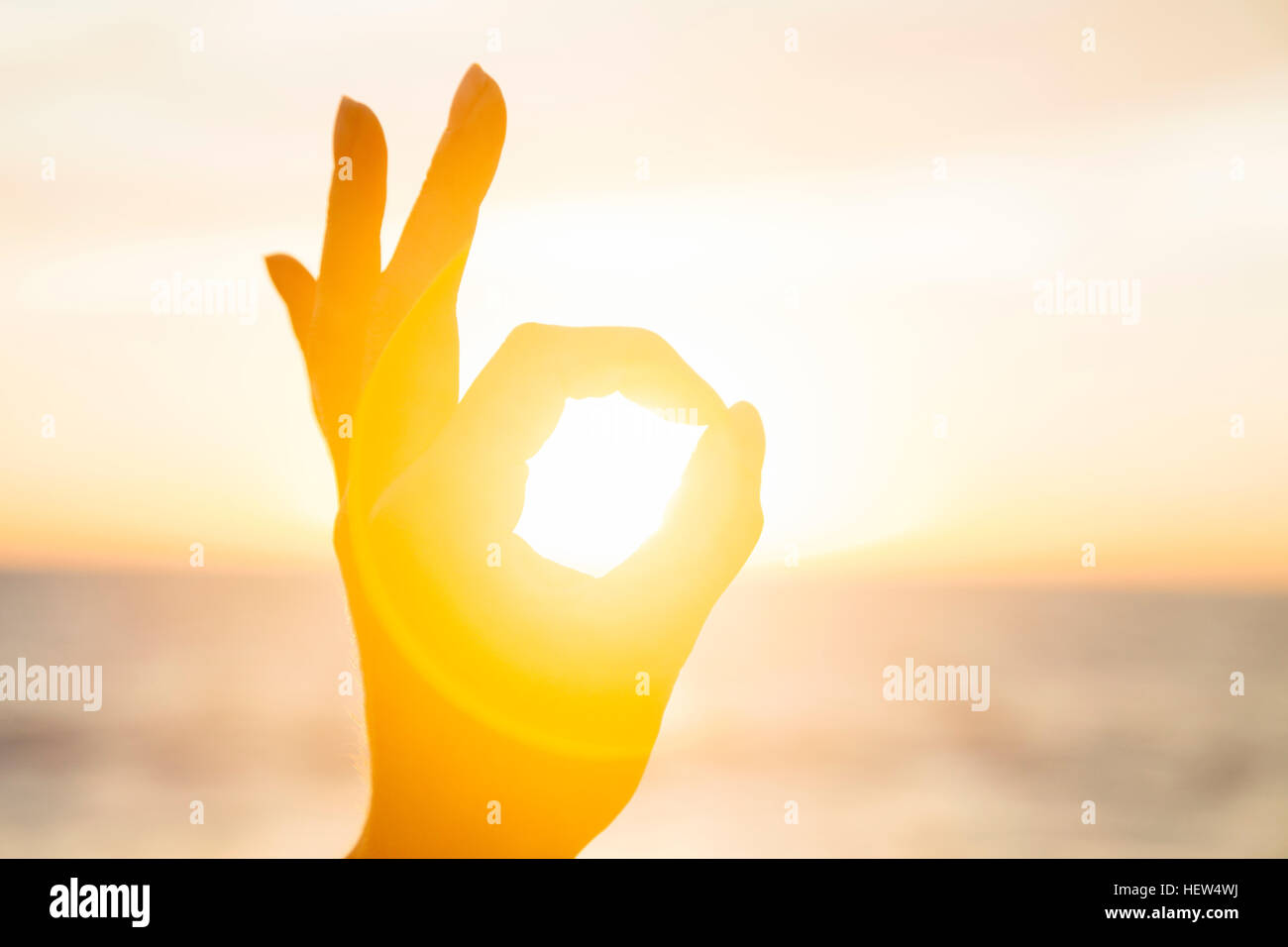 Woman circling the sun with fingers at sunrise Stock Photo - Alamy