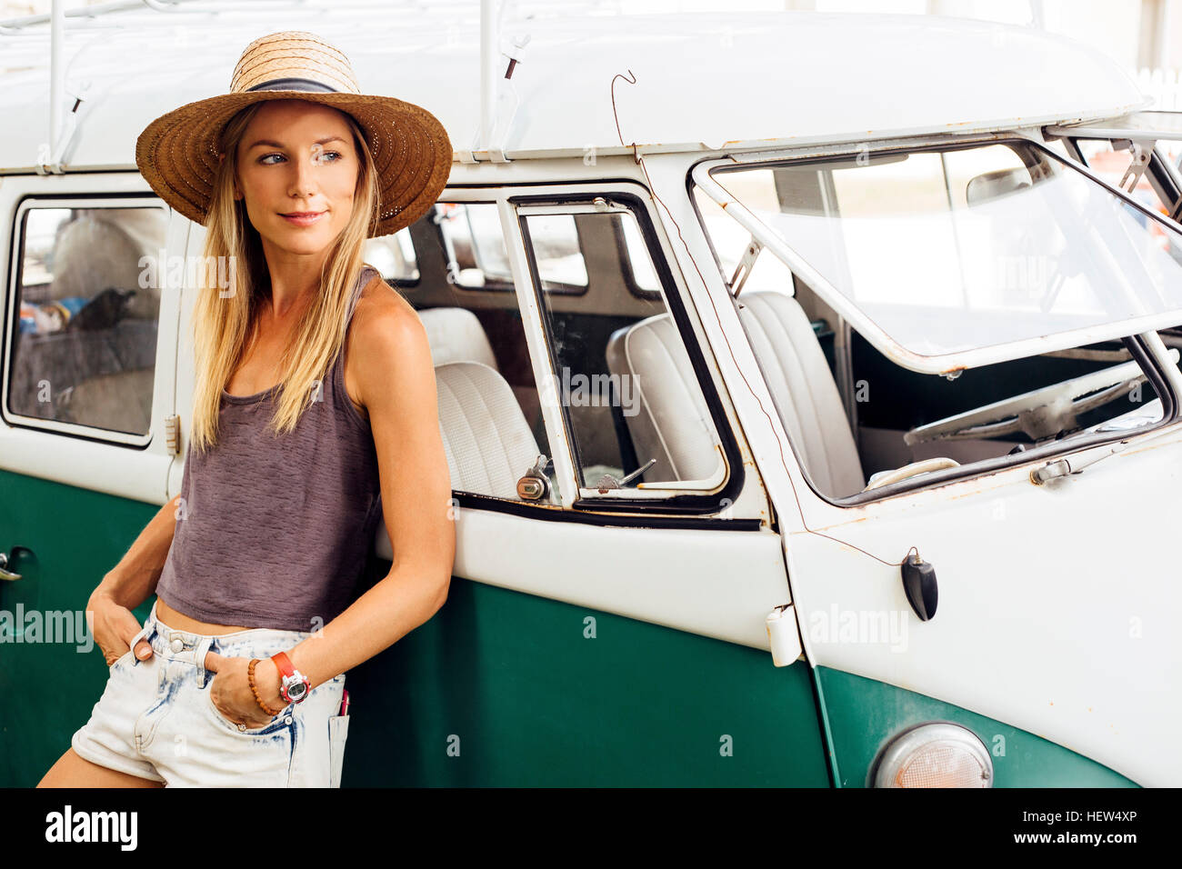 Woman leaning against vintage camper van looking away Stock Photo - Alamy