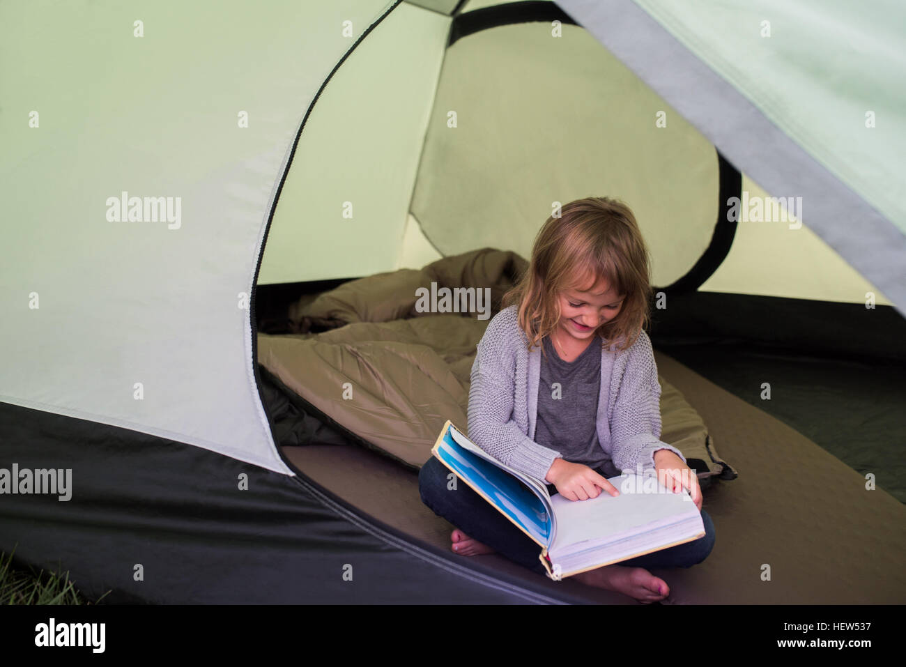 Young girl sitting in tent, reading book Stock Photo - Alamy