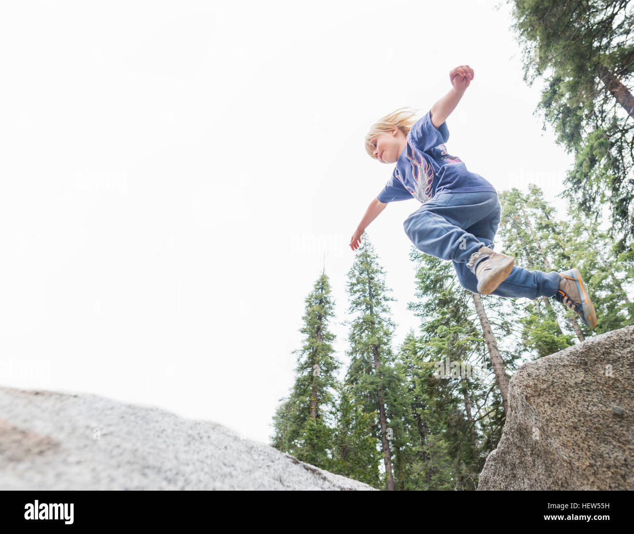 Young boy jumping off rock, low angle view, Sequoia National Park ...