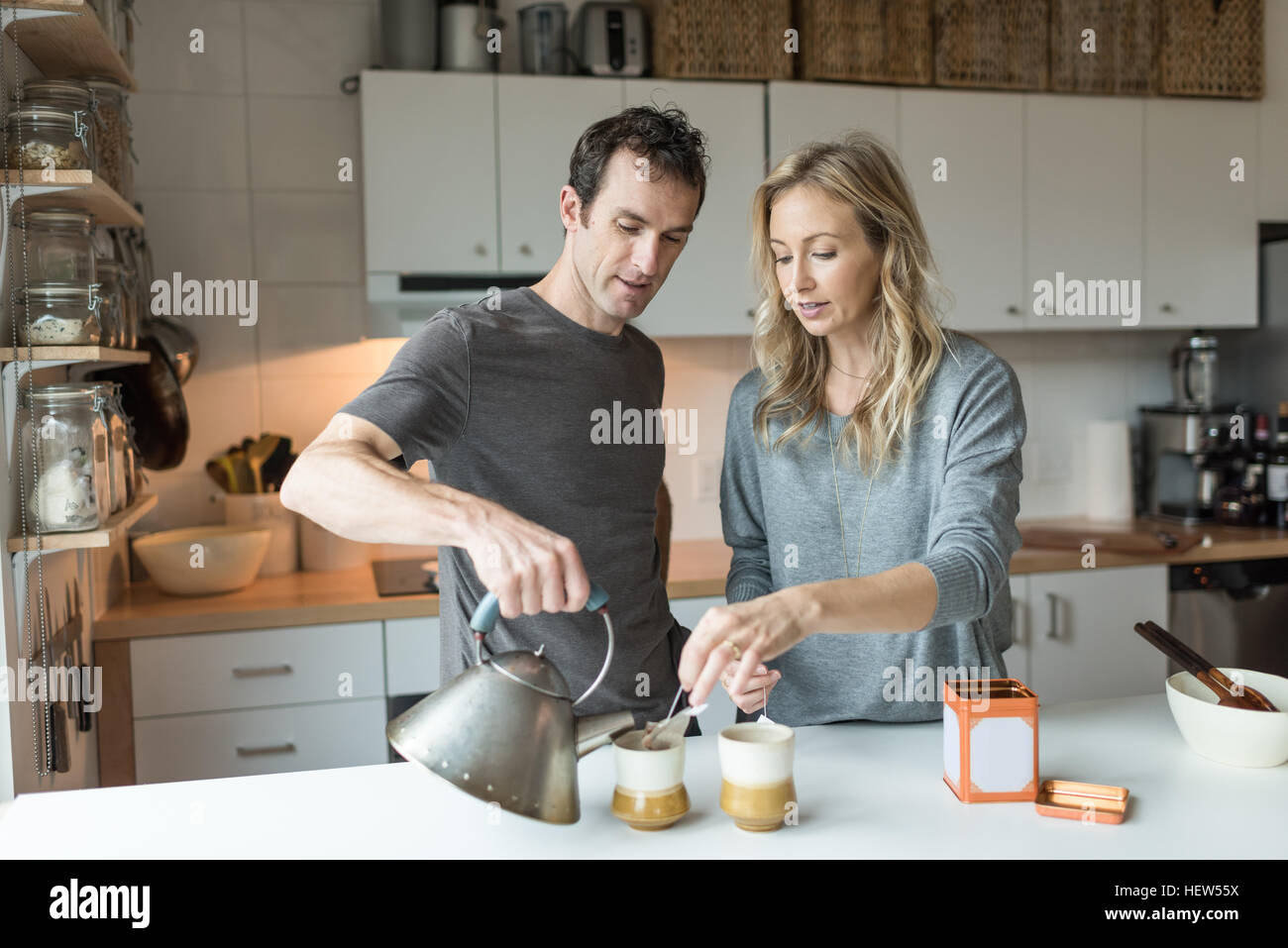 Mid adult couple making cup of tea in kitchen Stock Photo - Alamy
