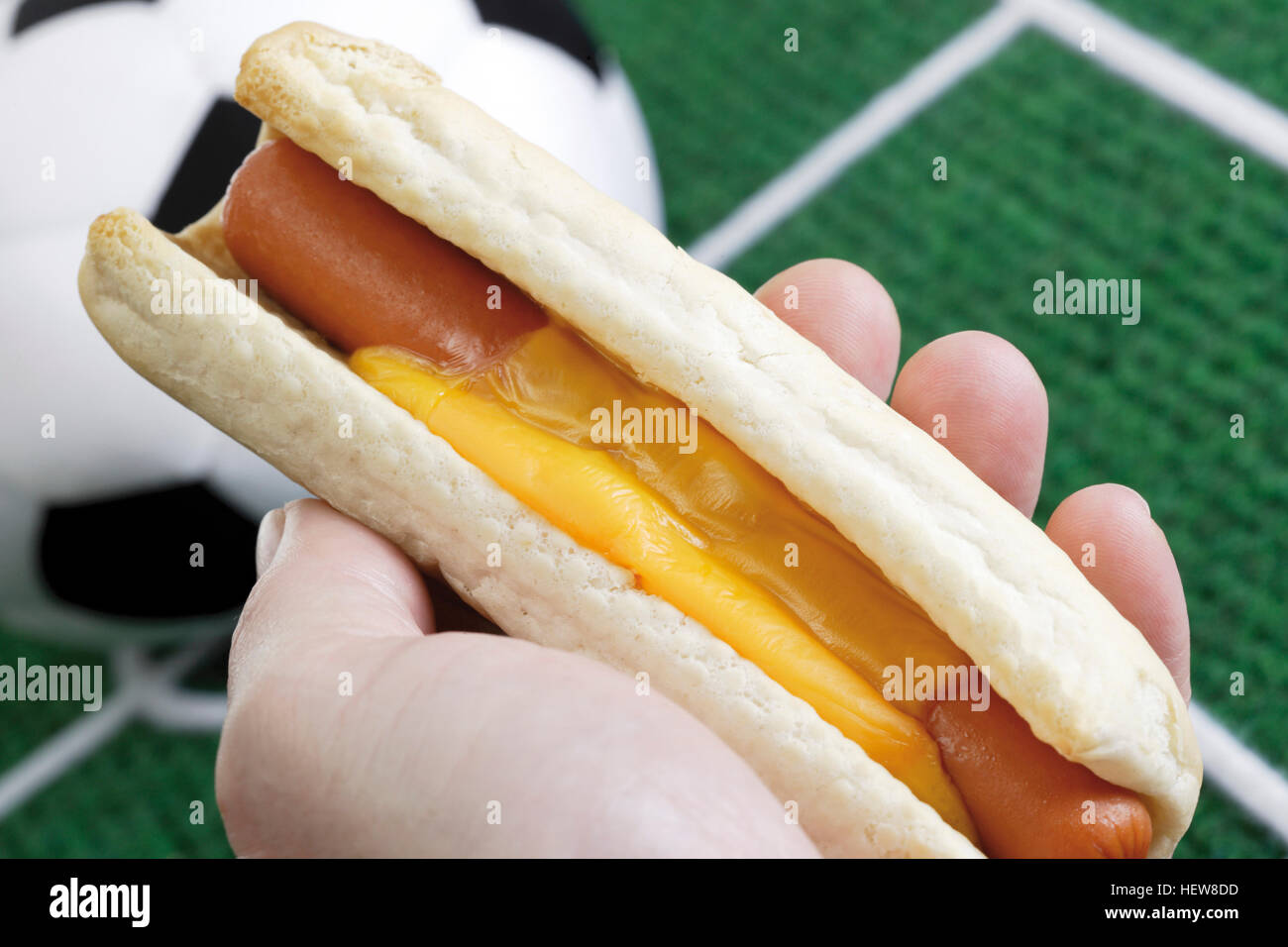 Hand holding hot dog, football and pitch Stock Photo - Alamy