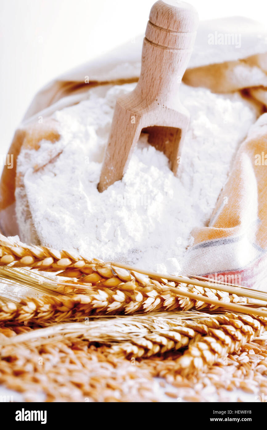 Flour in a sack, wooden measuring spoon, ears of dried wheat and loose ...