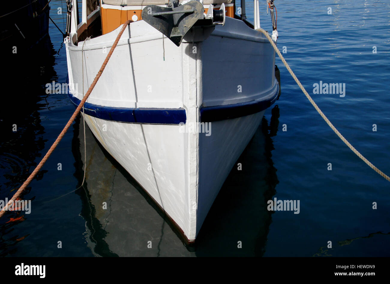A fishing boat with a well-defined bow reflects on the calm water. The ...