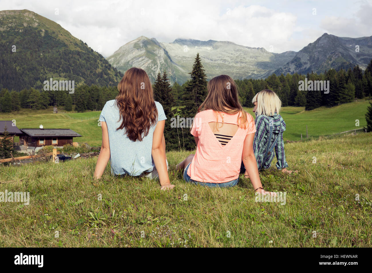 Rear view of three female adult friends looking out at Austrian Alps ...