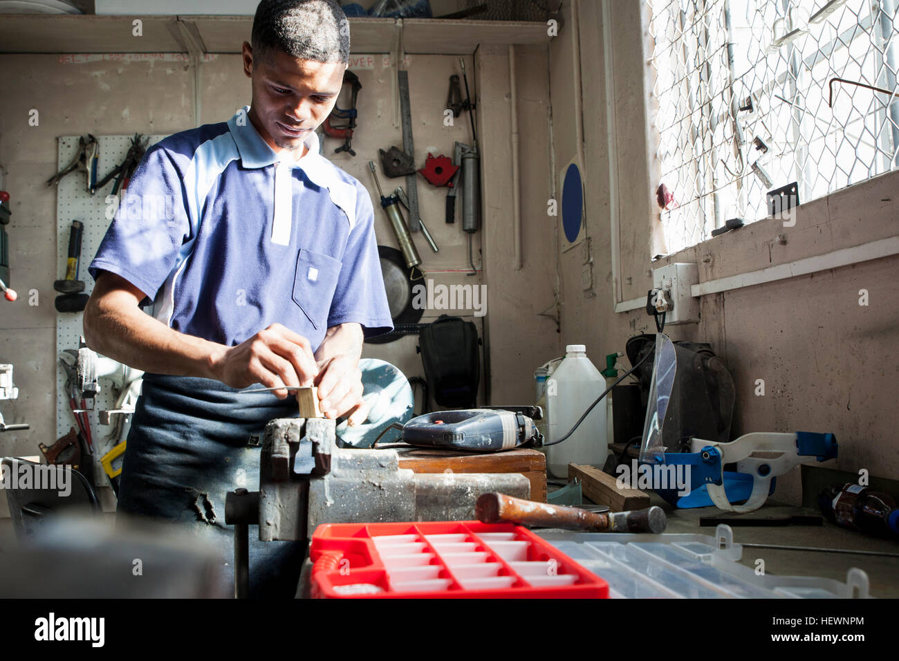 Young man working at vice in repair workshop Stock Photo - Alamy