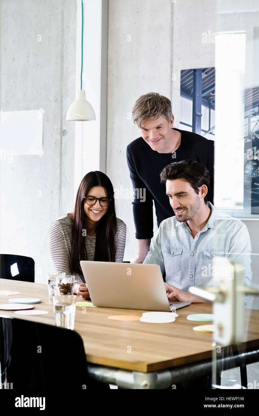 Colleagues in office using laptop smiling Stock Photo - Alamy