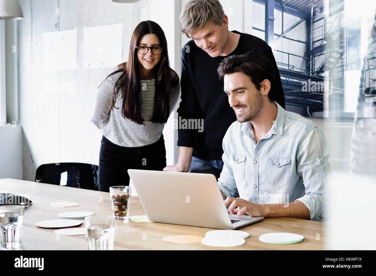 Colleagues in office using laptop smiling Stock Photo - Alamy