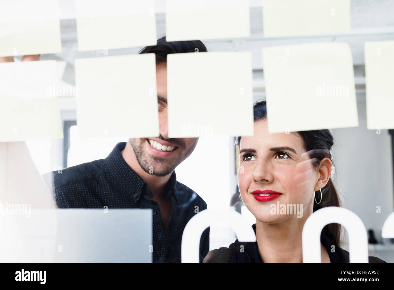 View through window of colleagues in office looking at sticky notes ...