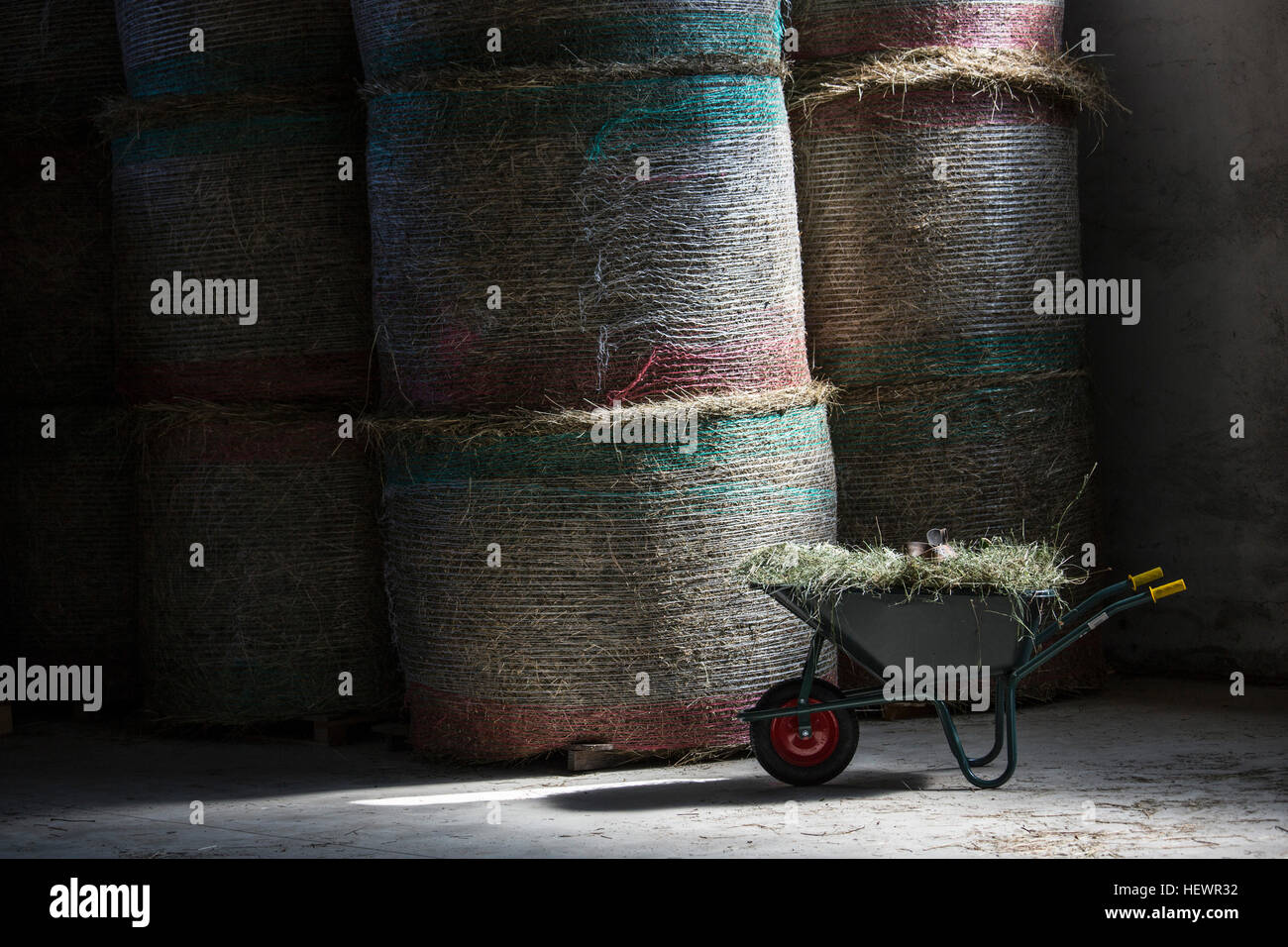 Wheelbarrow and haystacks in farm barn Stock Photo - Alamy