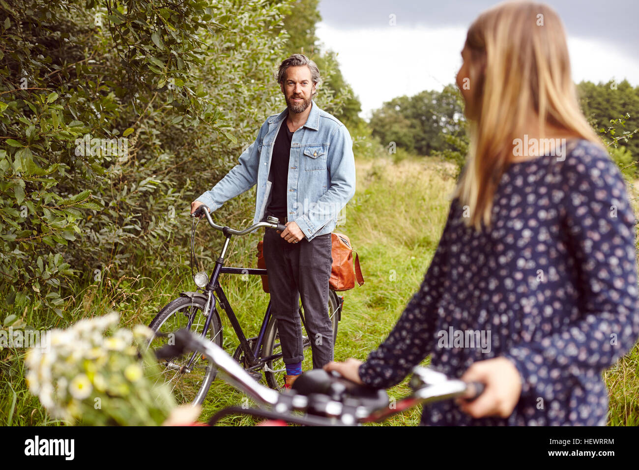 Female cyclist looking back at boyfriend on rural path Stock Photo - Alamy