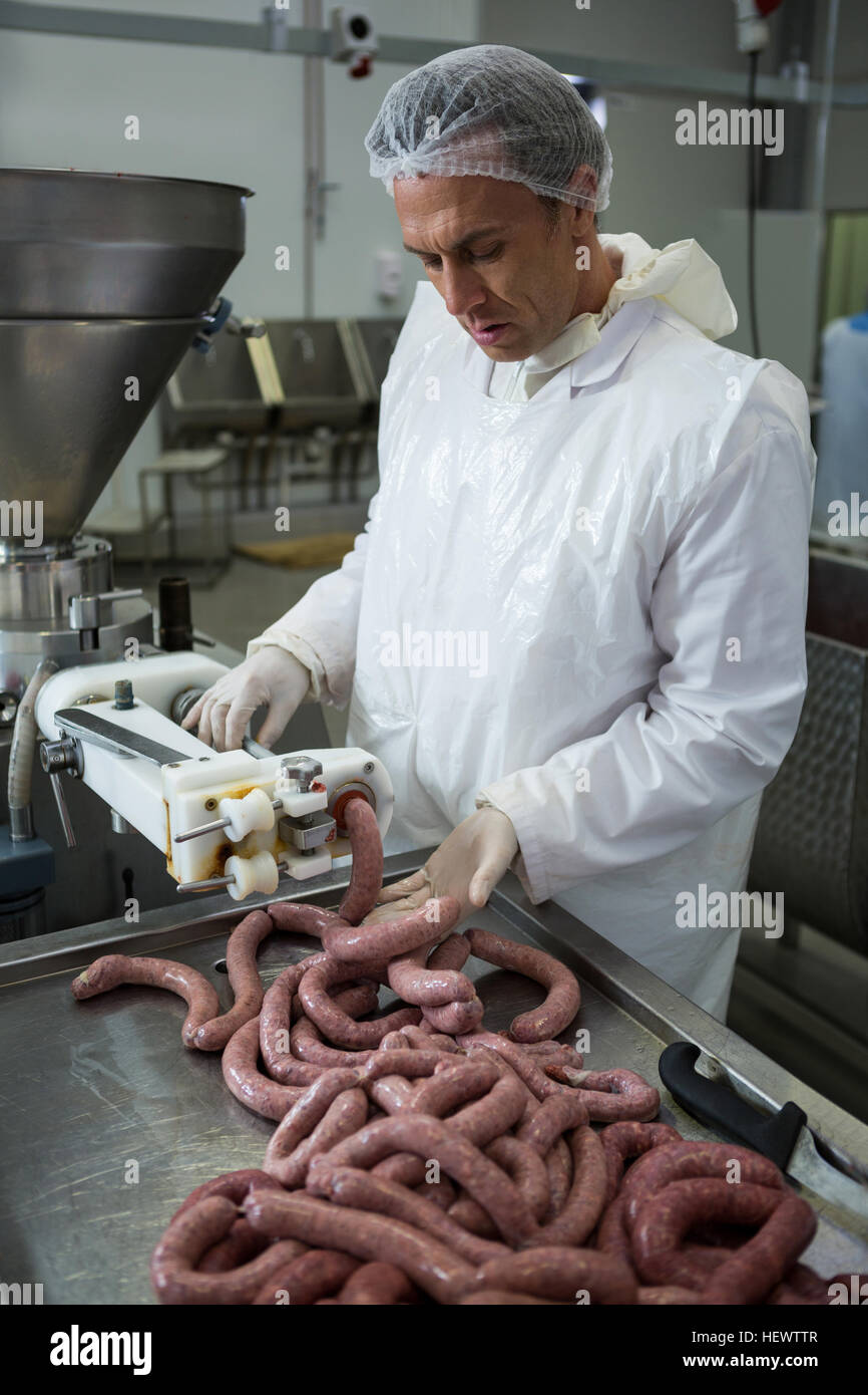 Butcher processing sausages at meat factory Stock Photo - Alamy