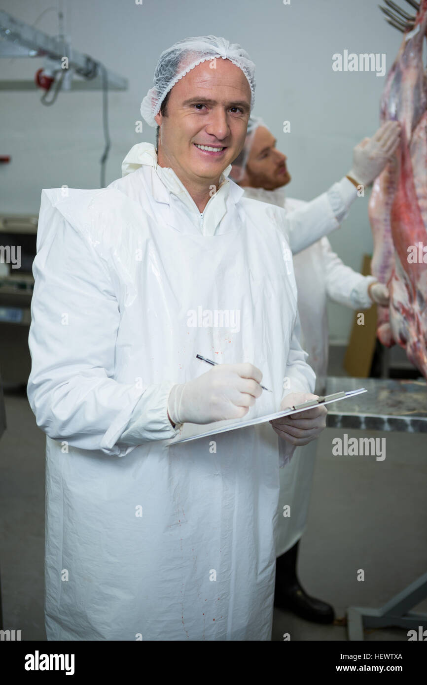 Portrait of male butcher holding clipboard at meat factory Stock Photo ...