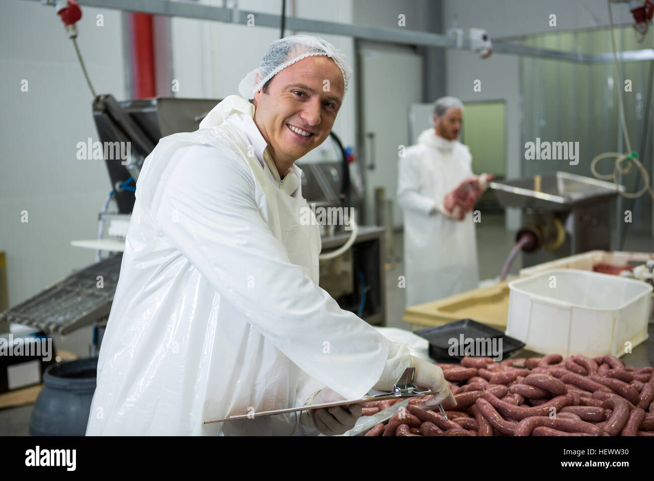 Portrait of male butcher maintaining records on clipboard at meat ...