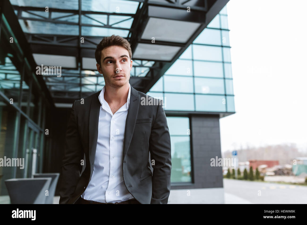 Cool business man in suit standing near the office and looking away ...