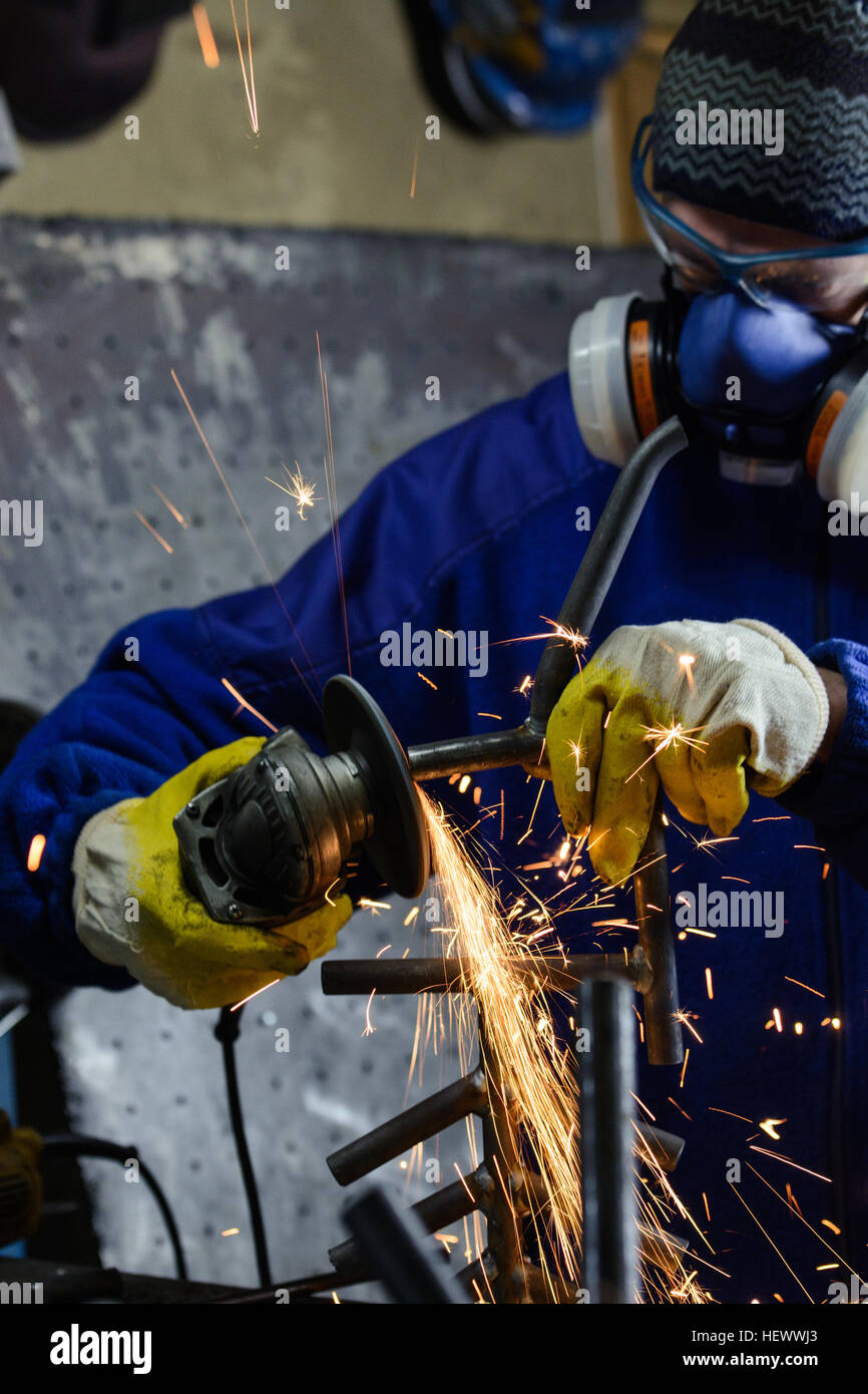 Man sawing metal with a rotary angle grinder on an aluminium surface ...