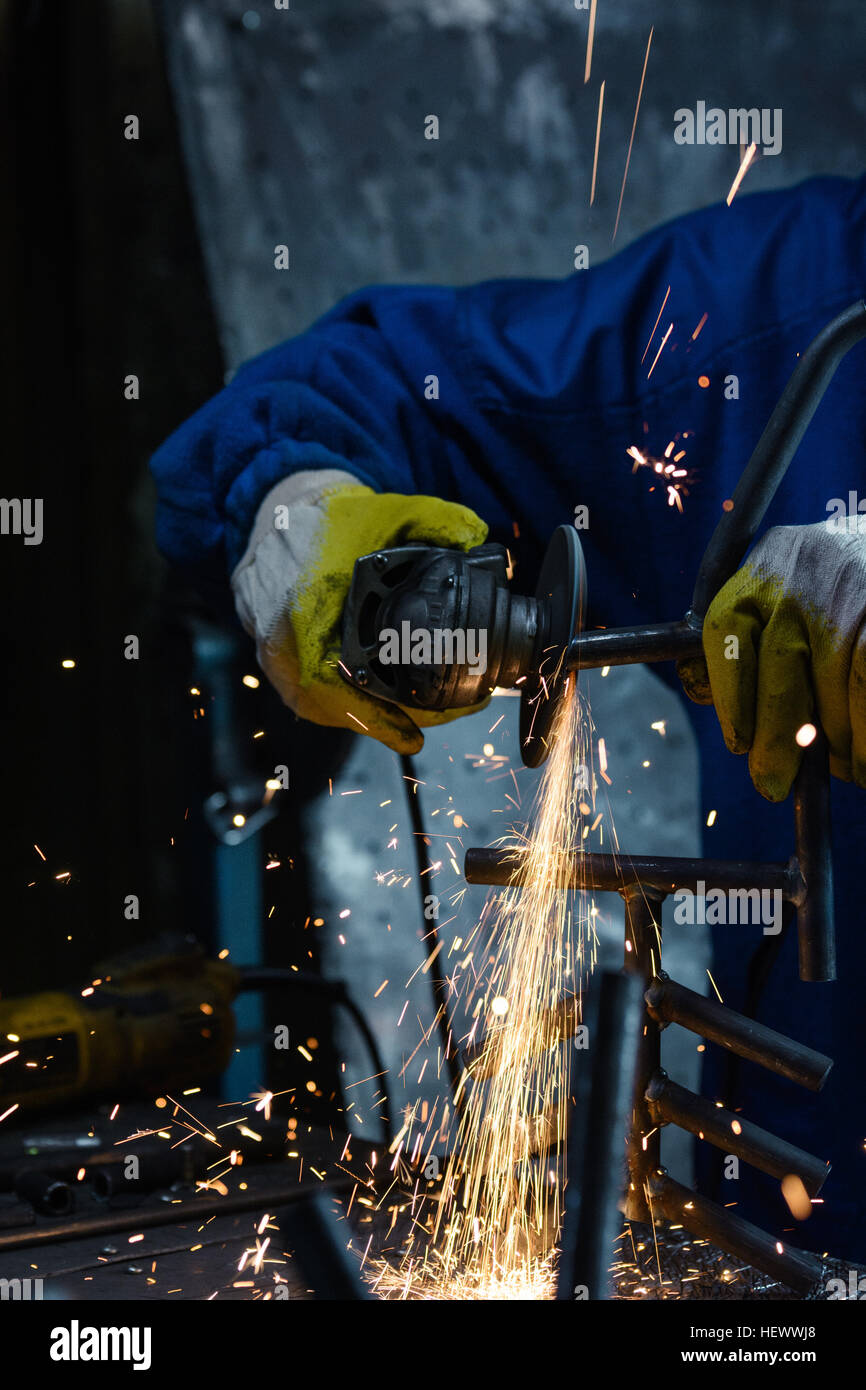 Man sawing metal with a rotary angle grinder on an aluminium surface ...