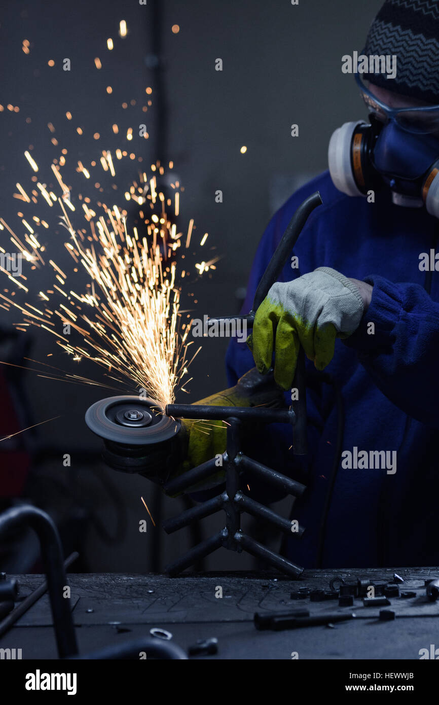Man sawing metal with a rotary angle grinder on an aluminium surface ...